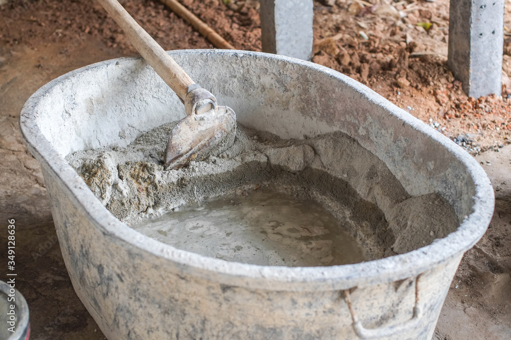 Mixing concrete by hands and spade in black basin in the construction ...