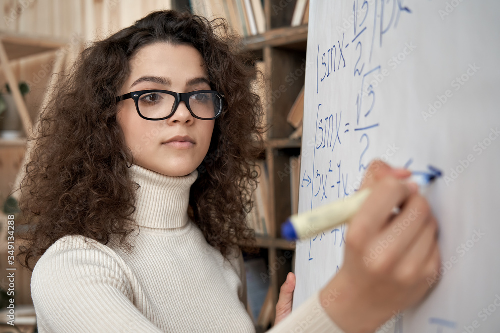 Young serious female latin math school teacher wearing glasses holding ...