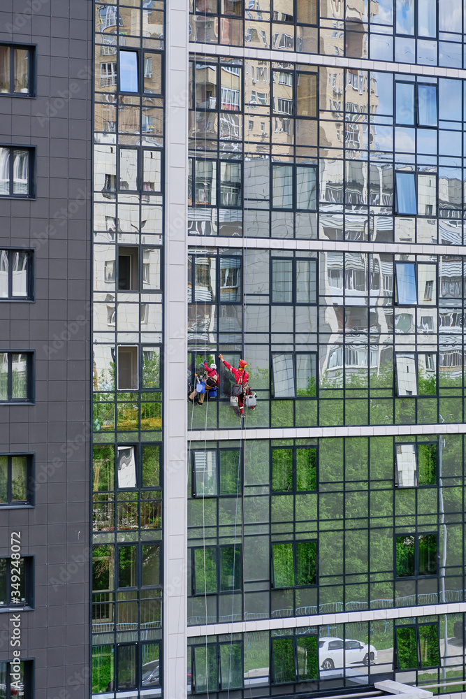 Two industrial climbers from the cleaning service wash the glass facade ...
