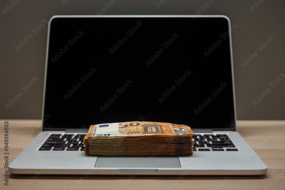 open laptop and stack of money euro banknotes Stock Photo | Adobe Stock