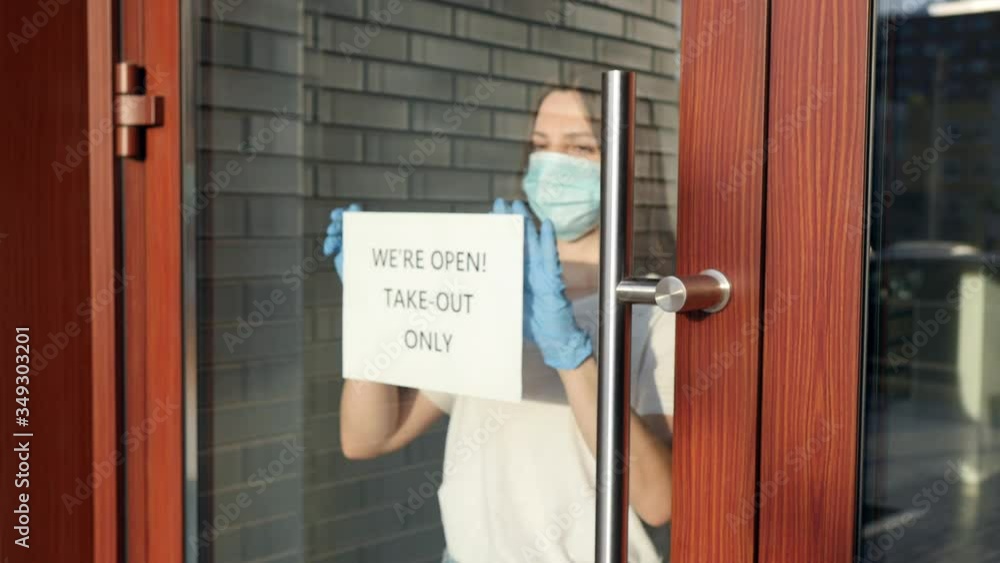 A cafe owner puts a TAKE OUT ONLY sign on the front door. Take out or ...
