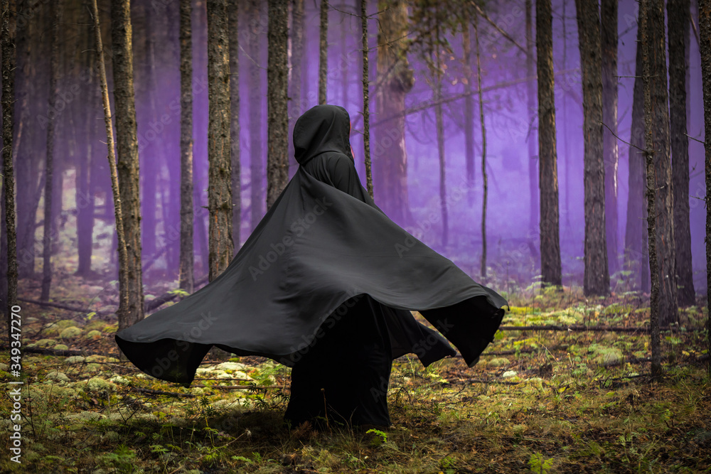 mystical girl in a raincoat with a hood in the forest with a purple ...