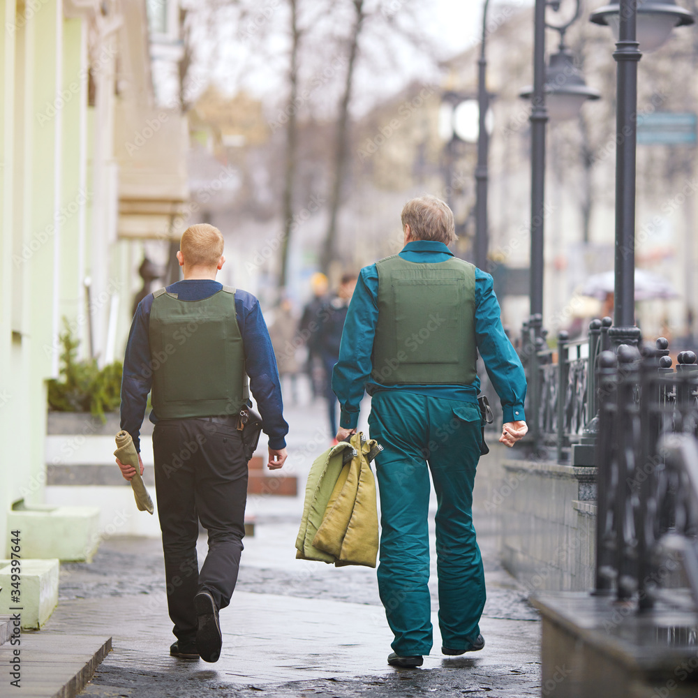 Armed Cash-in-transit guard walking with money bags walking down the ...