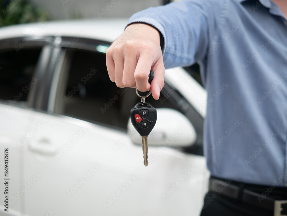 Man holding key in modern auto dealership. Close up hand of cardealer ...