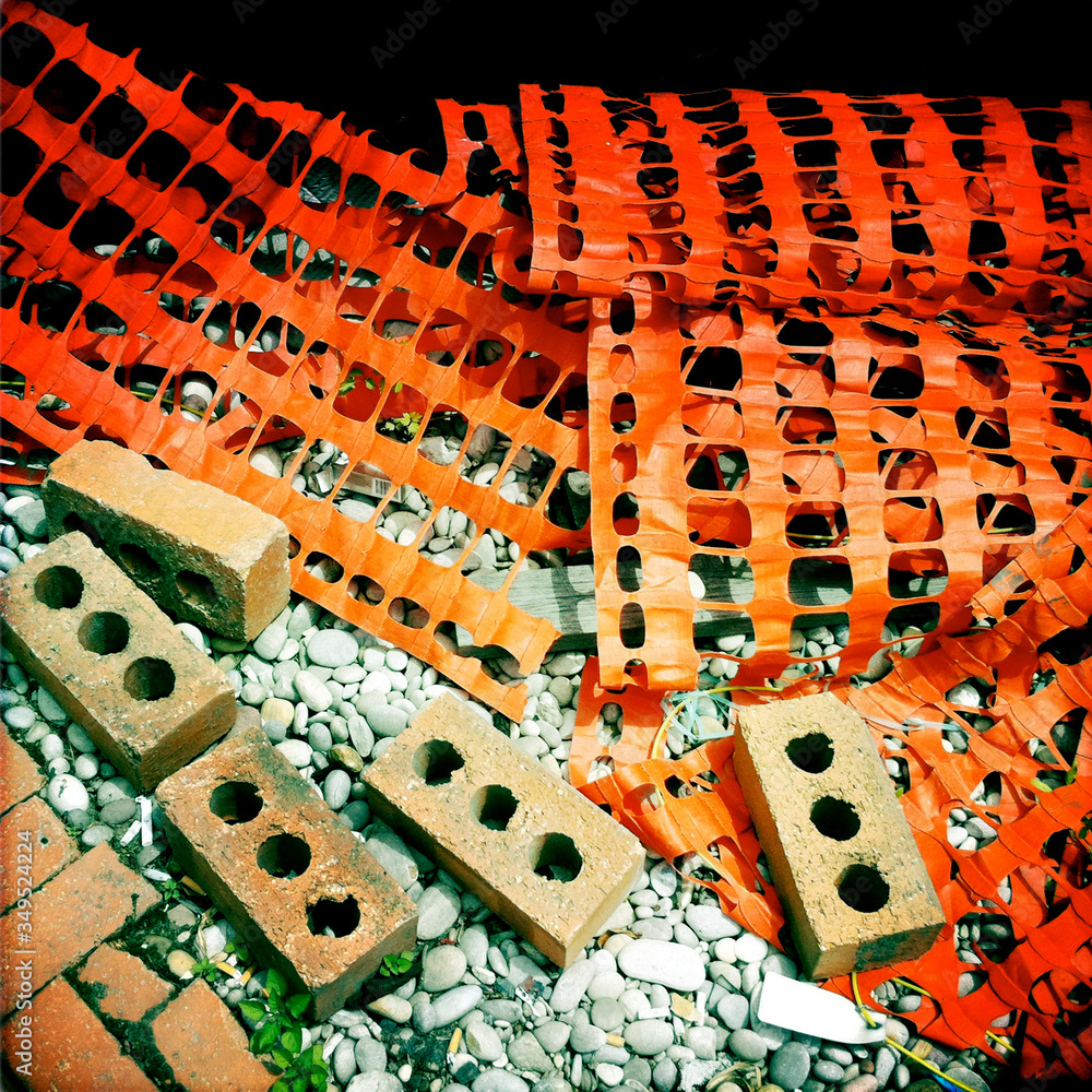 Orange plastic safety barrier and loose bricks lying around on a ...