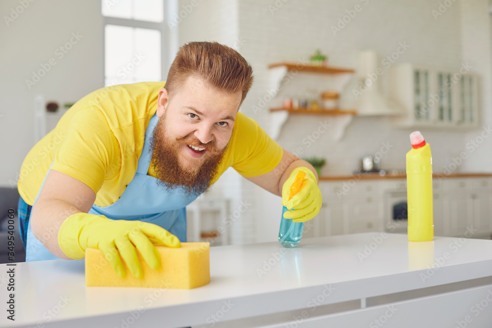 Funny fat man with a beard in an apron washing cleans the room in the ...
