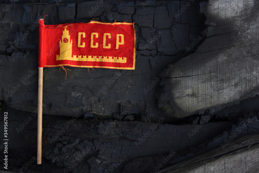 The old small flag of the Soviet Union on burnt boards. symbol of the ...