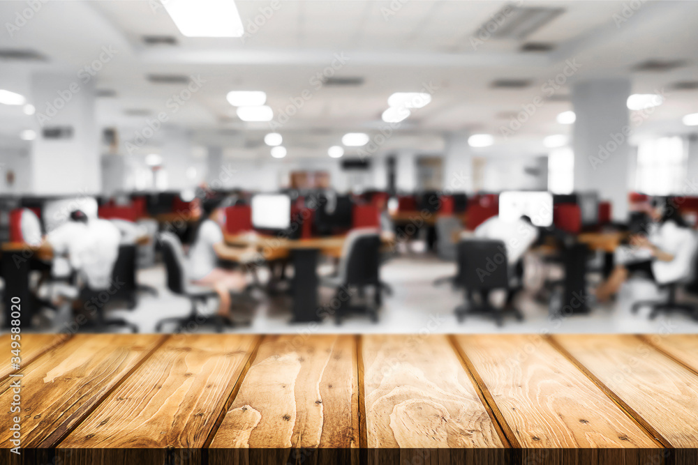 Empty wooden desk space over blurred office or meeting room background ...