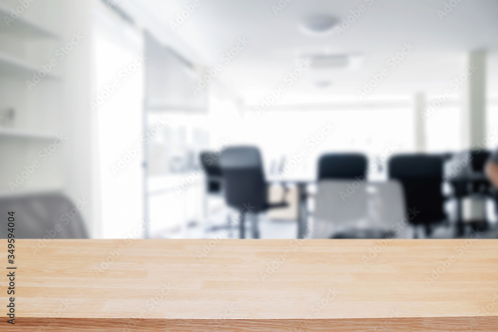 Empty wooden desk space over blurred office or meeting room background ...