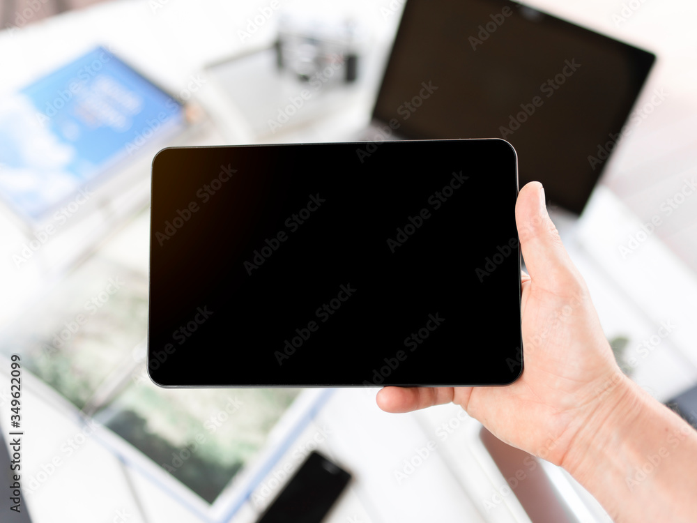 Hand holding a tablet with a black background - in the background a ...