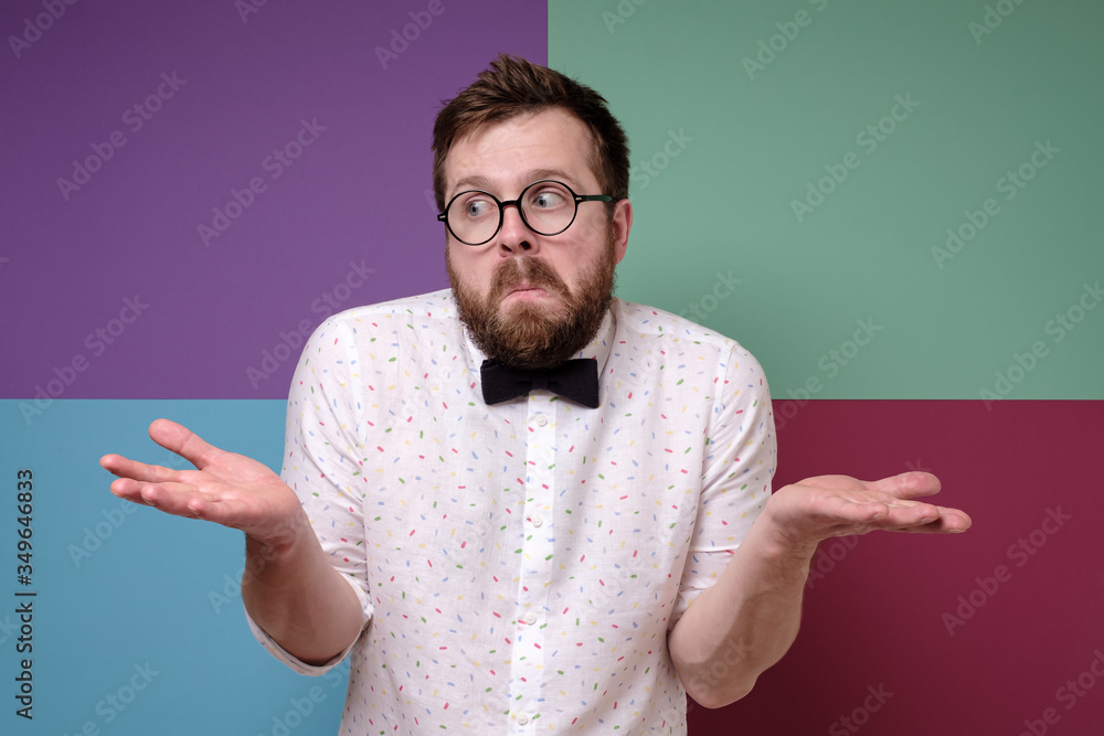 Funny man with an innocent and embarrassed expression shrugs and ...