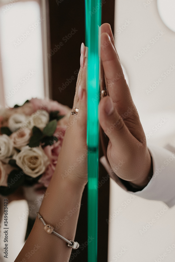 Touching hands of isolated from each other people through the glass ...