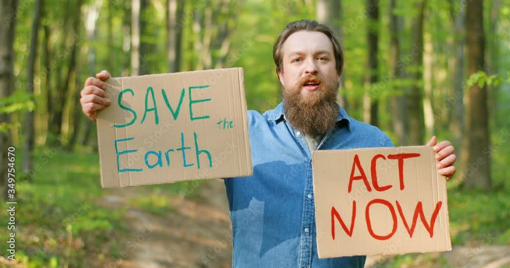 Portrait shot of Caucasian young male eco acivist standing in green ...
