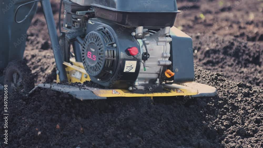 Close up, Man plowing the land in the garden with a cultivator ...