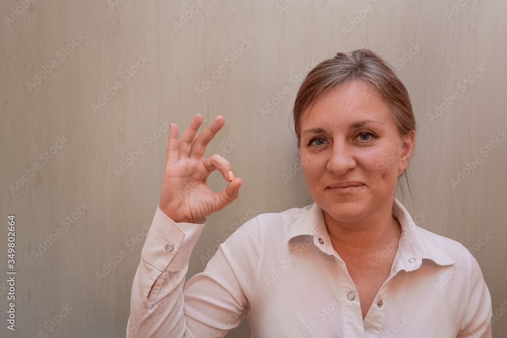Middle aged woman portrait. OK hand gesture of 40 years woman looking ...