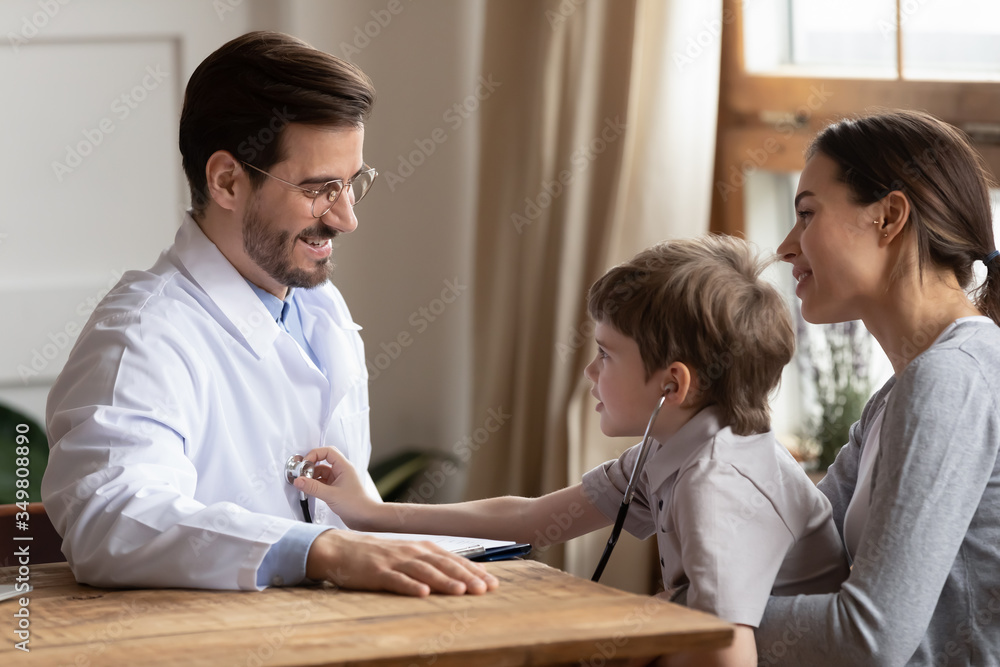 Excited little boy patient have fun play with male pediatrician listen ...