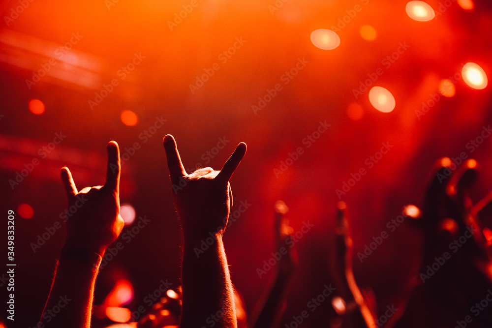 fans showing signs of the horns during a rock band concert in a club. A ...