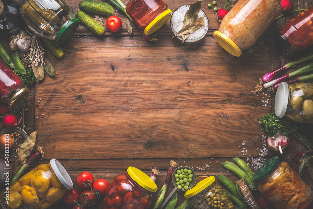Wooden food background with various preserved vegetables in jars with ...