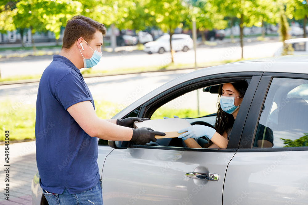 Food delivery courier gives pizza to woman in eco car. Safety food ...