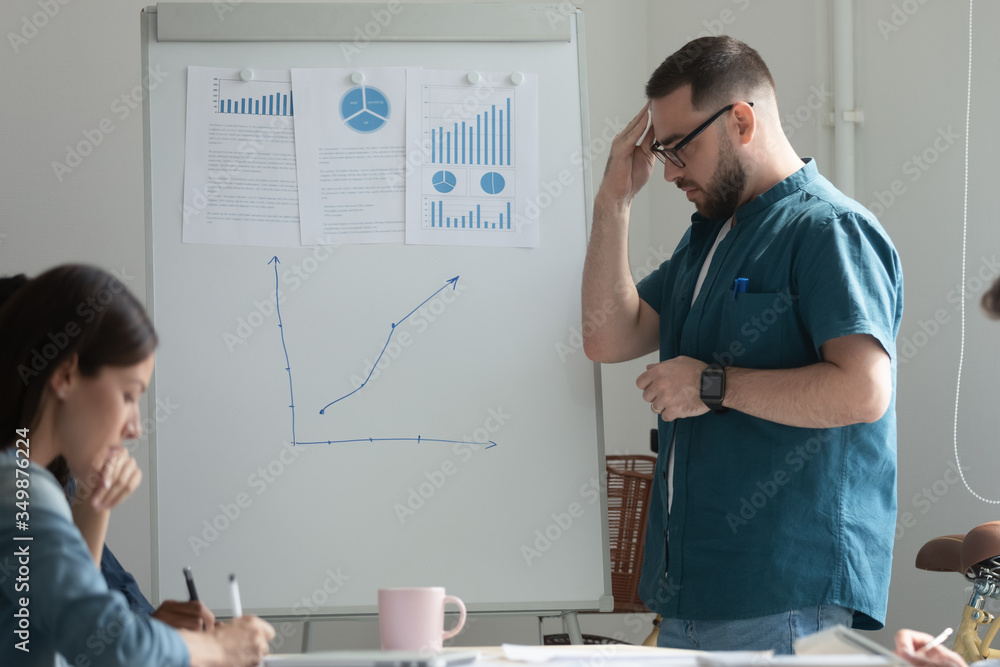 Stressed businessman touching forehead at flip chart presentation ...