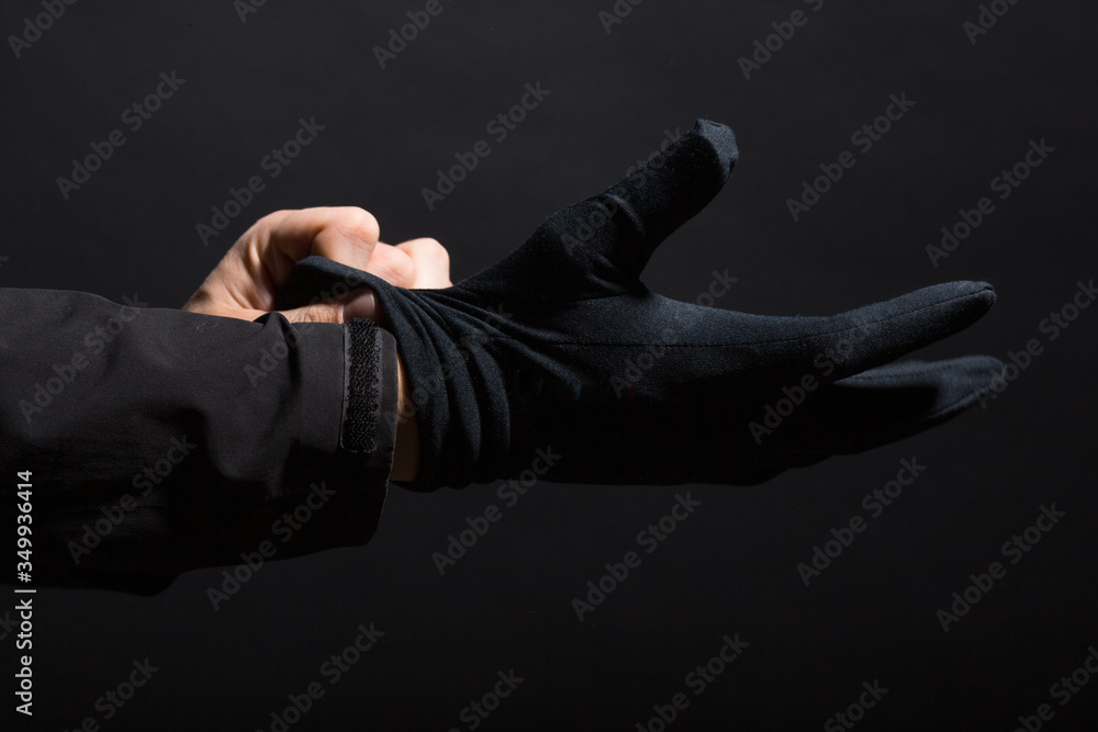 Hand in black gloves of a crime on a black background. Gloves are worn ...