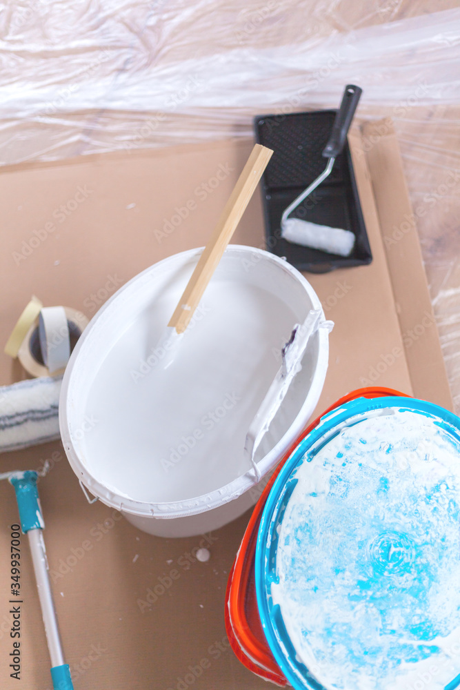 Paint bucket with white wall paint and with wooden stirring rod and ...