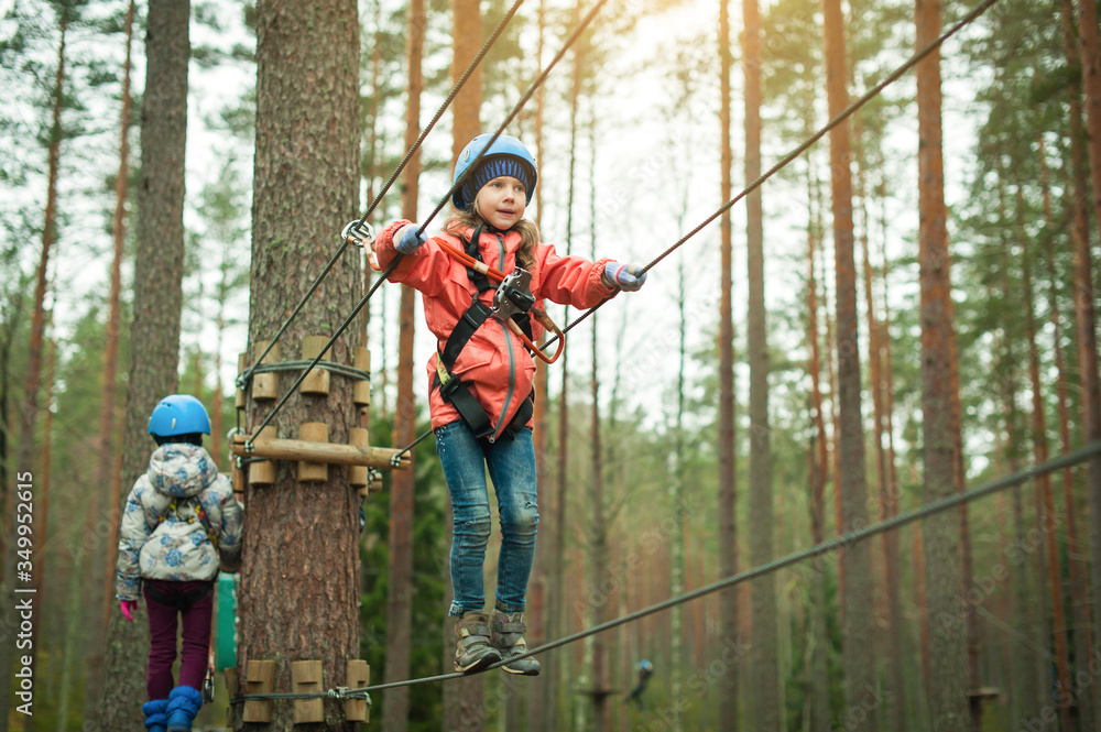girl goes on a rope in a rope park, a climbing center. she is scared ...