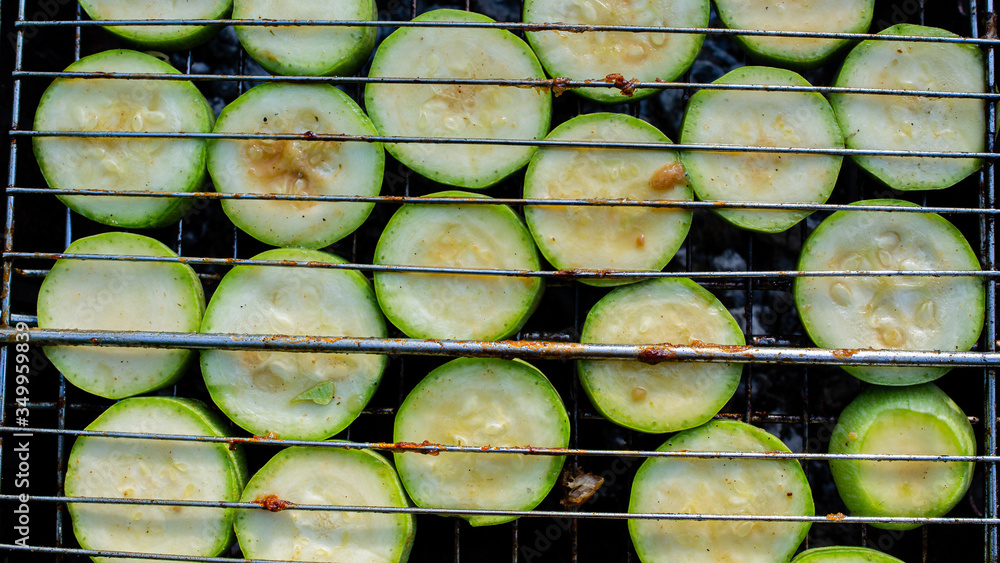 Cooking courgettes on the grill. Green courgettes are fried at a ...