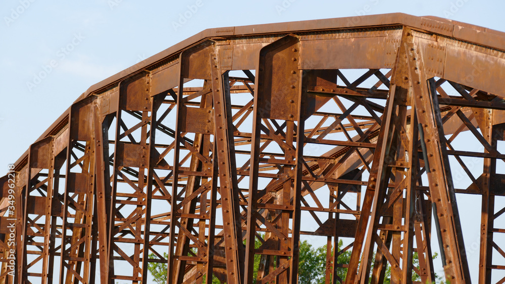 An old disused rusted brown bridge in the countryside connecting two ...