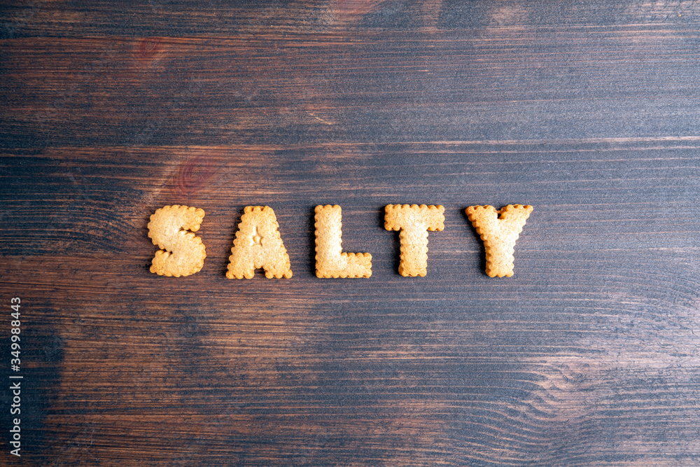 The word salty written with letters of cracker biscuits on rustic ...