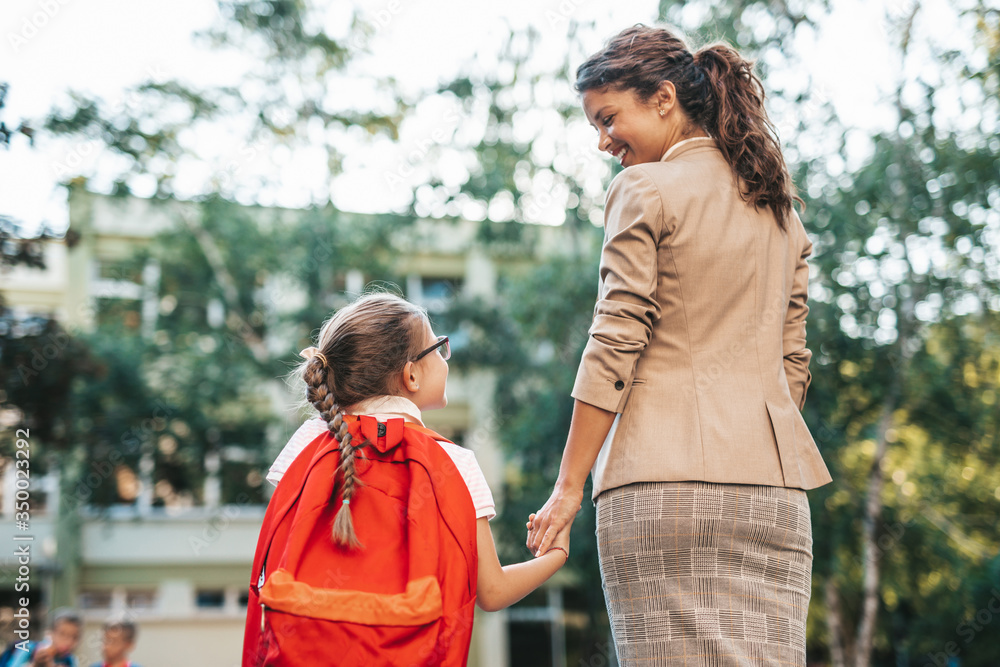First day at school. Mother leads a little child school girl in first ...