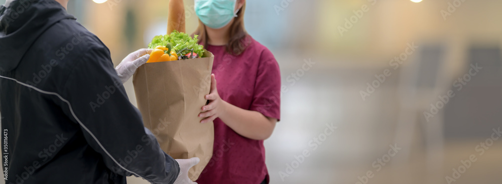 Female customer receiving fresh food bag from delivery service man at ...