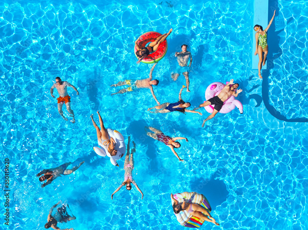 Aerial of friends having party in swimming pool with inflatable ...