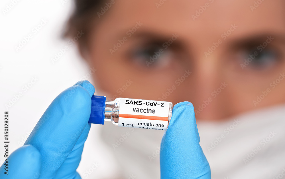 Hand in blue medical gloves holds small vial with label SARS-Cov-2 ...