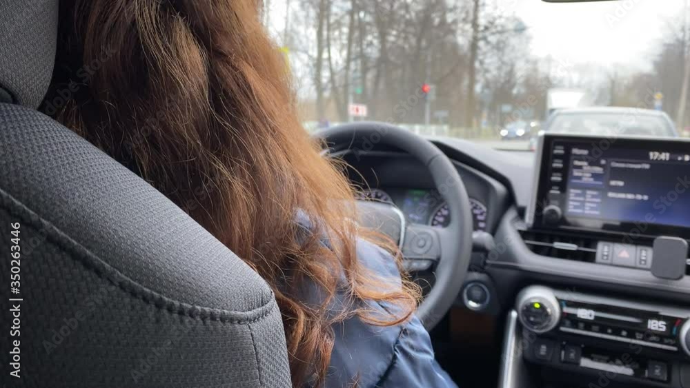 Rear view of brunette woman driving her car through the city streets ...