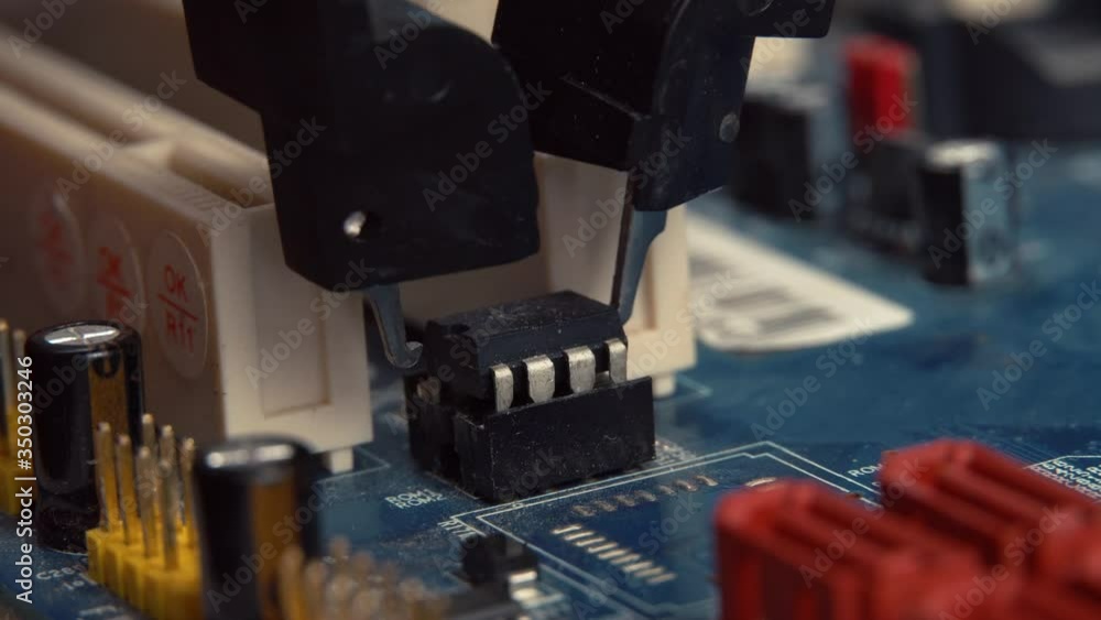 An engineer removes the programmable BIOS chip with the tongs from the ...