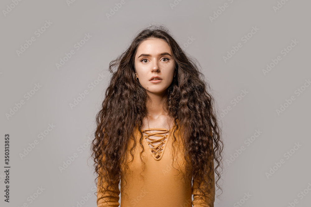 Ruffled scared woman with voluminous curly long hair with bewilderment ...