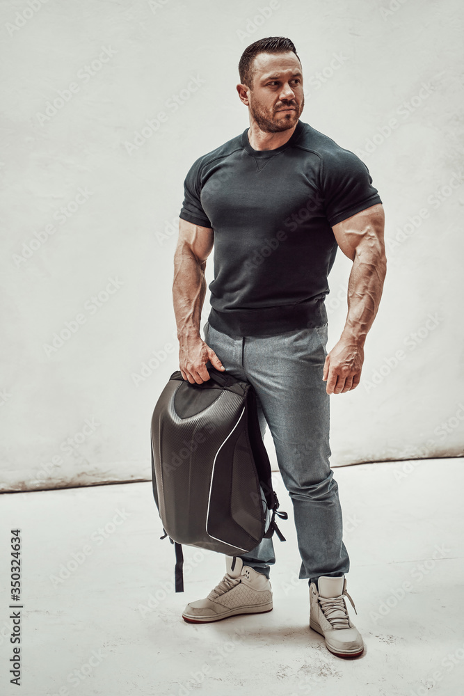 Full height photo of an athlete posing with a backpack and casually ...