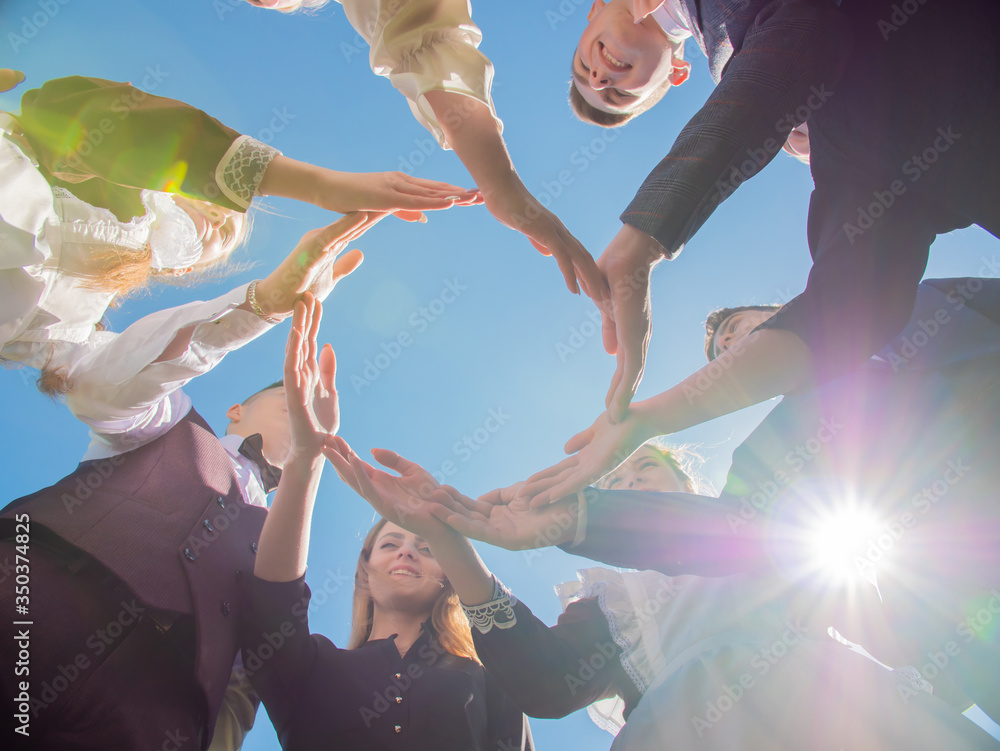 A group of friends make a circle shape out of their hands. The concept ...