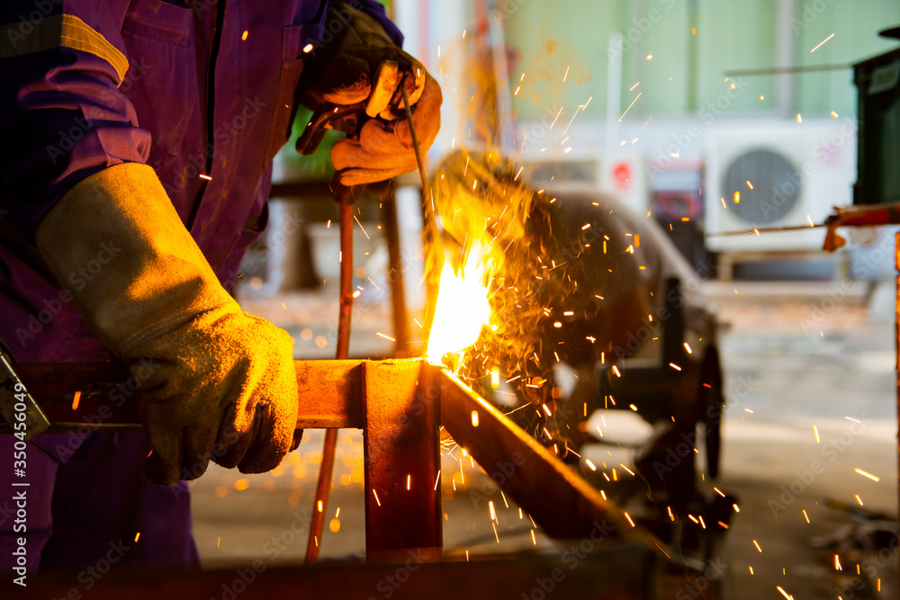 Welder is assembling the workpiece by process shielded metal arc ...