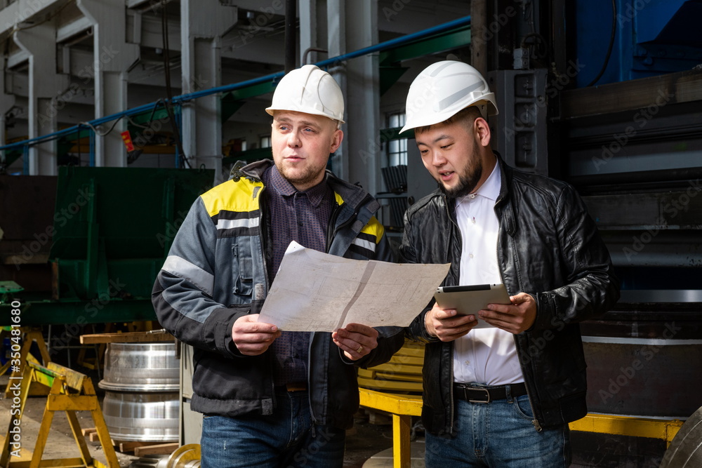 Two young engineers at a modern factory. The photo illustrates new ...