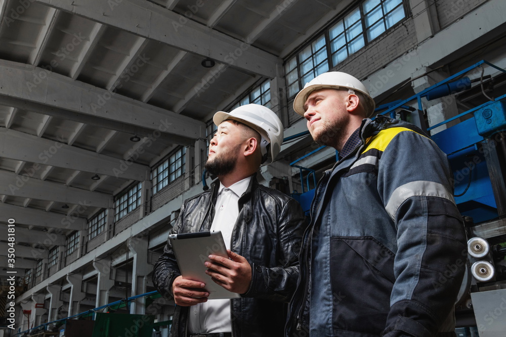 Two young engineers at a modern factory. The photo illustrates new ...