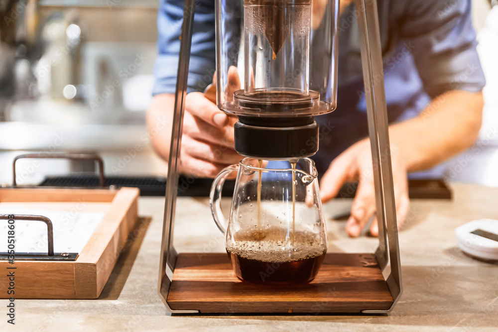 Male barista making pour-over coffee with alternative method called ...
