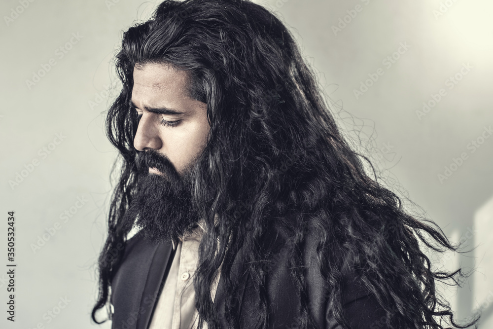 side view of handsome bearded man with a long hair, posing in studio ...