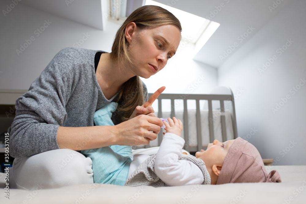Young mom soothing baby daughter, making strict face, showing index ...