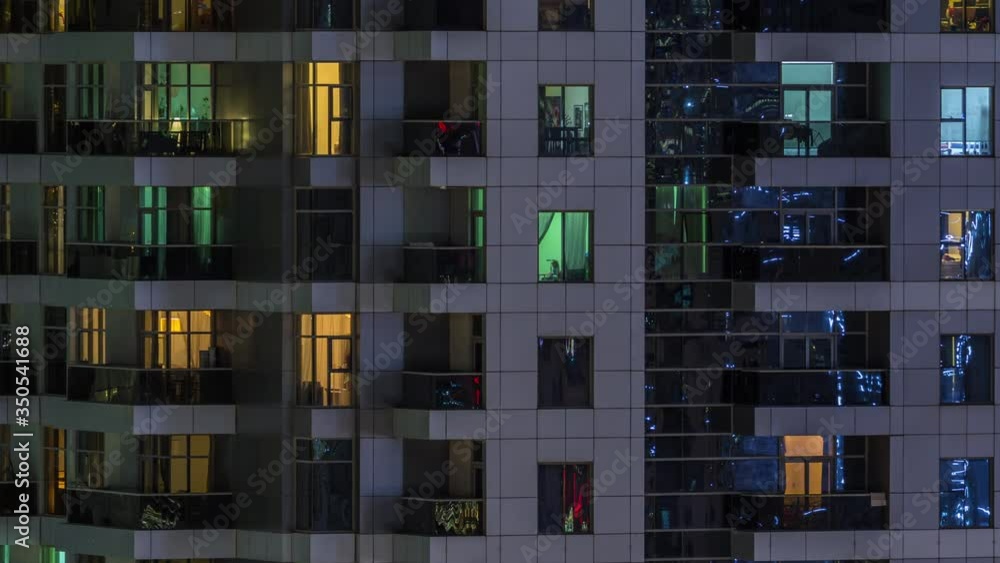 Rows of glowing windows with people in the interior of apartment ...