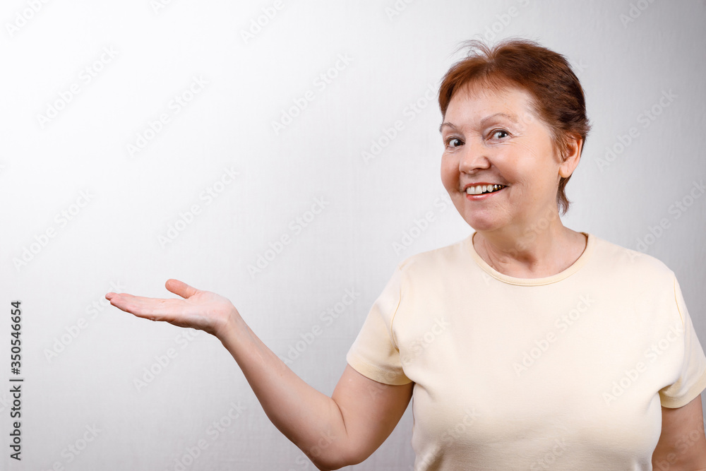beautiful senior woman shows a hand to the side on a white background ...