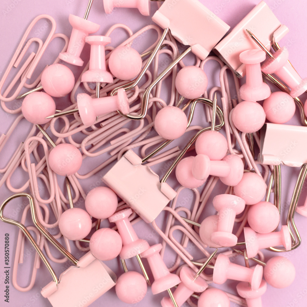Texture made of paper clips and push pins on a pink pastel background ...