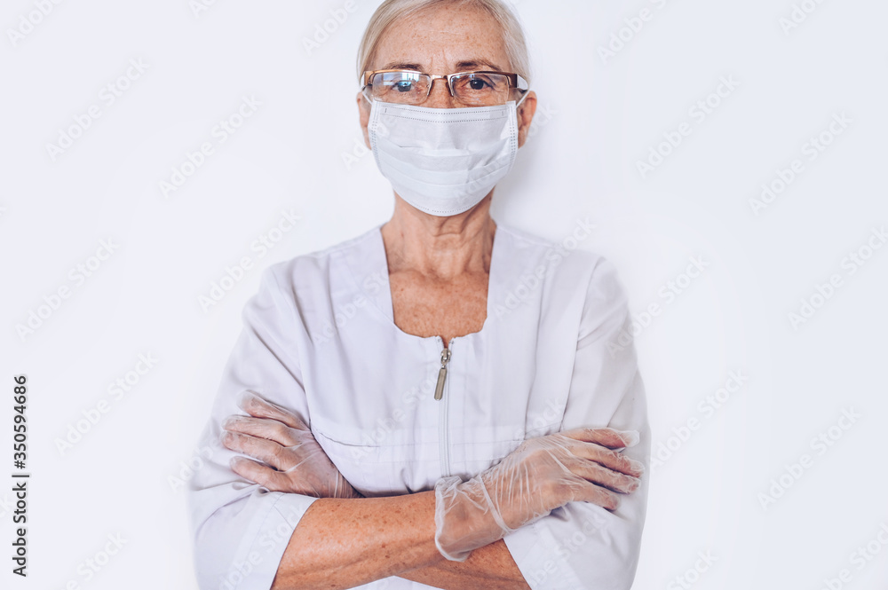 Elderly mature woman doctor or nurse crossed arms in a white medical ...