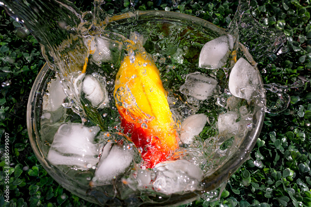 Bolis de mango con chile chamoy cayendo en agua con hielos naranjú ...